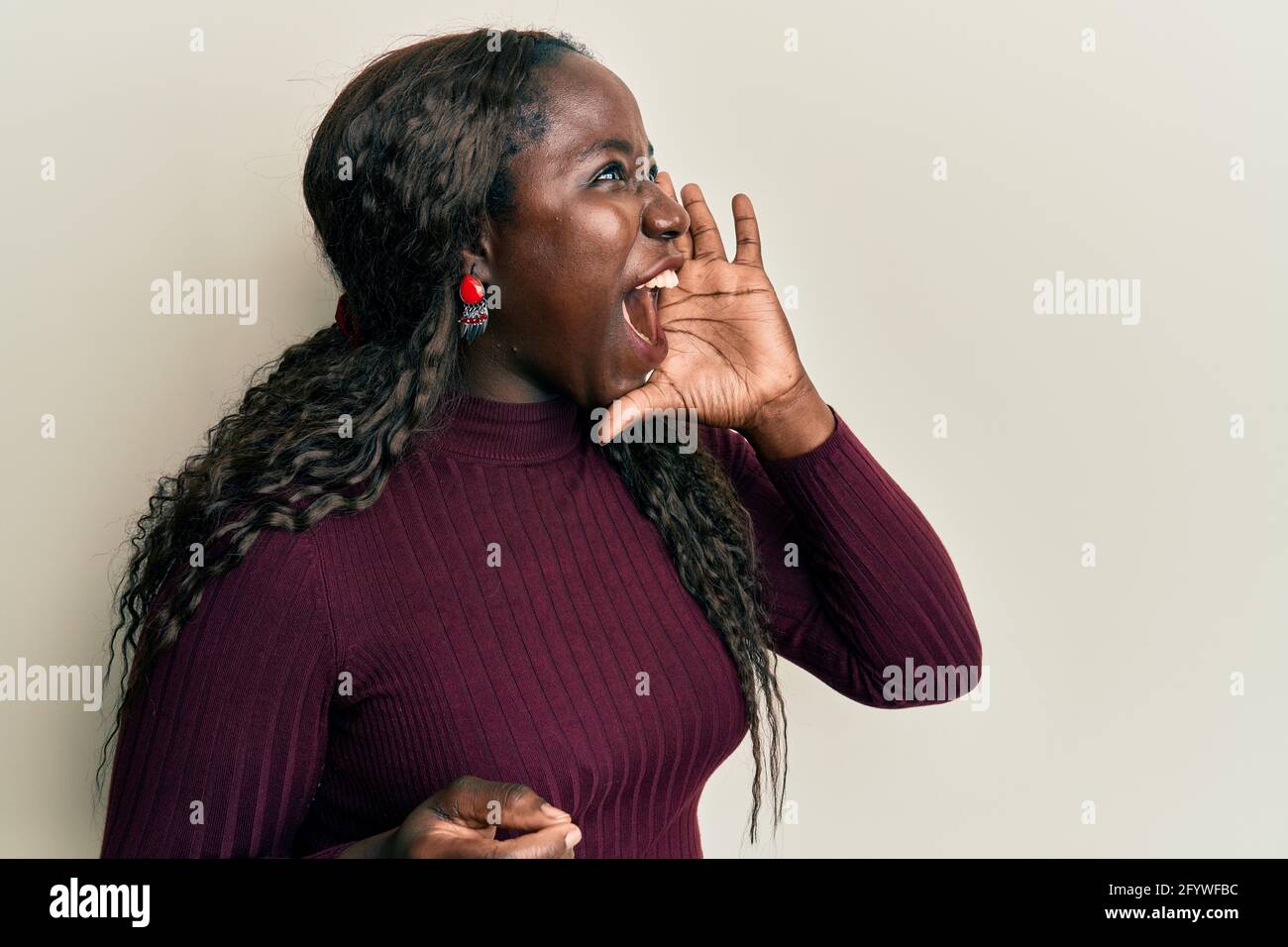 African young woman wearing casual clothes shouting and screaming loud ...