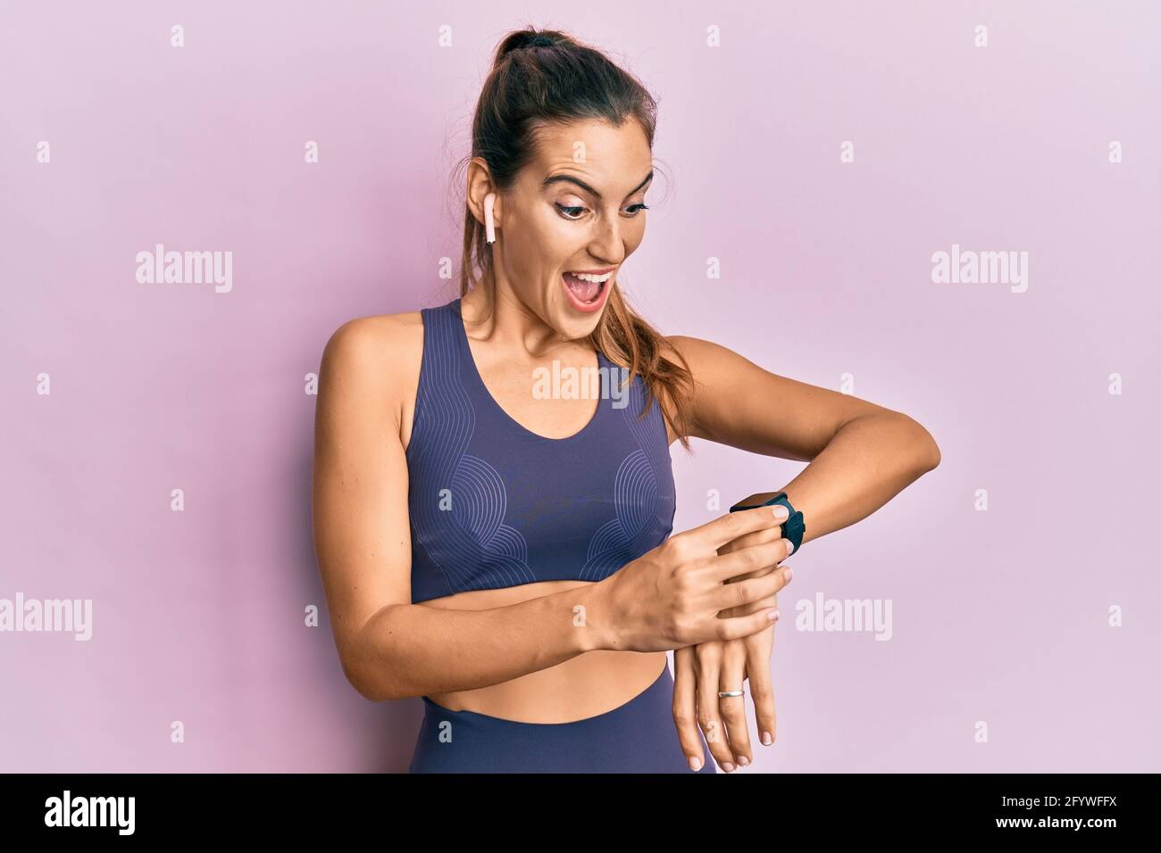Young beautiful woman wearing gym clothes, using earphones and smart ...