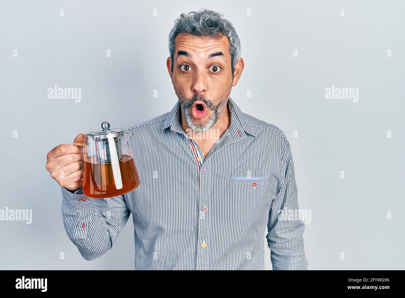Handsome middle age man with grey hair holding traditional tea pot ...