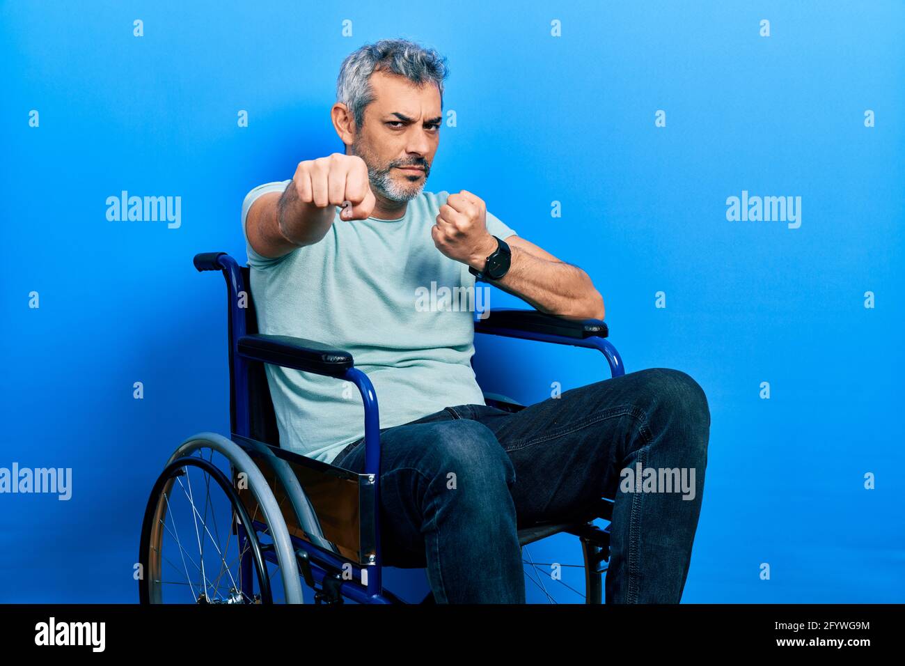 Handsome middle age man with grey hair sitting on wheelchair punching ...