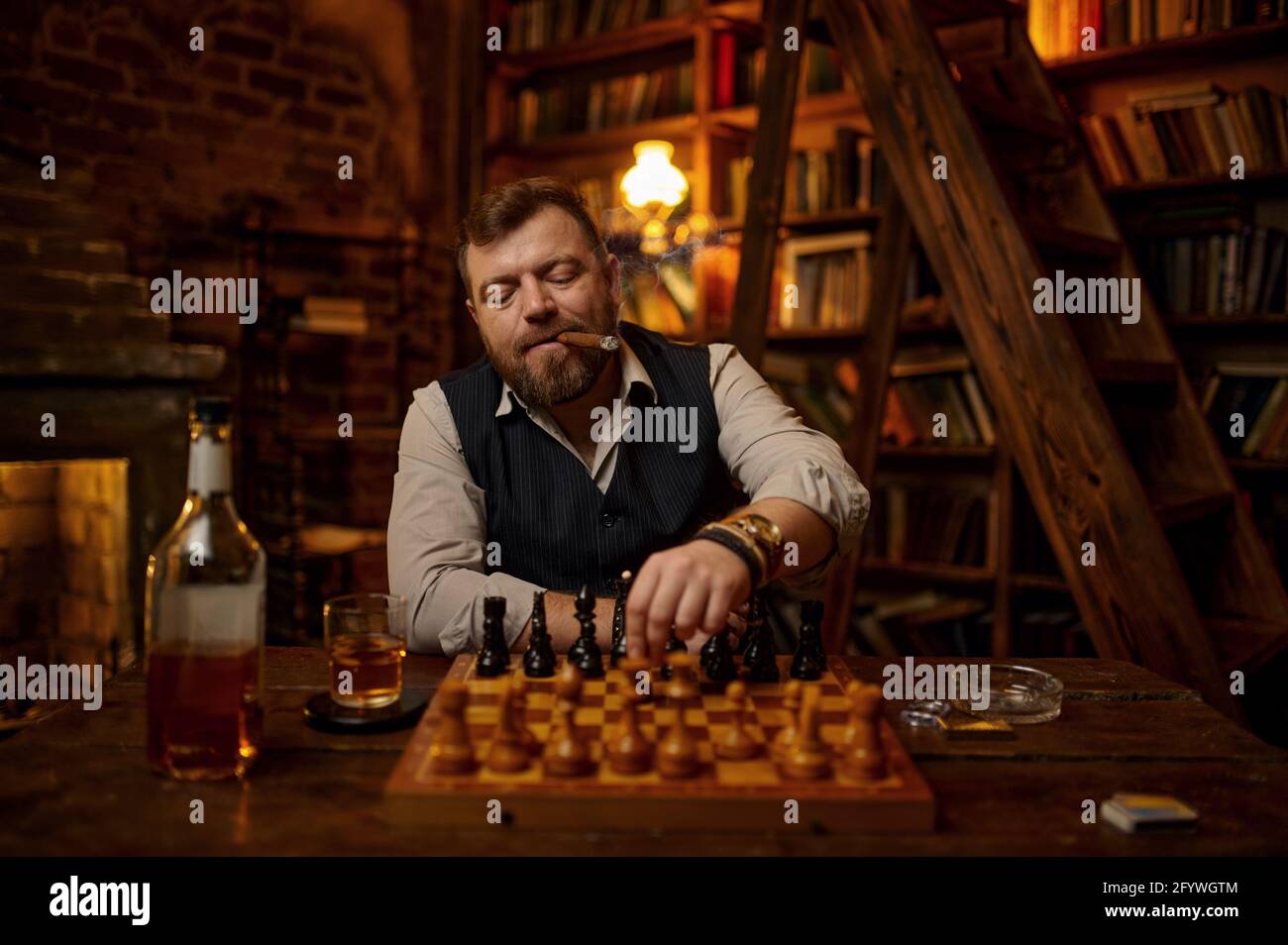 Man smokes a cigar and play chess in office Stock Photo - Alamy