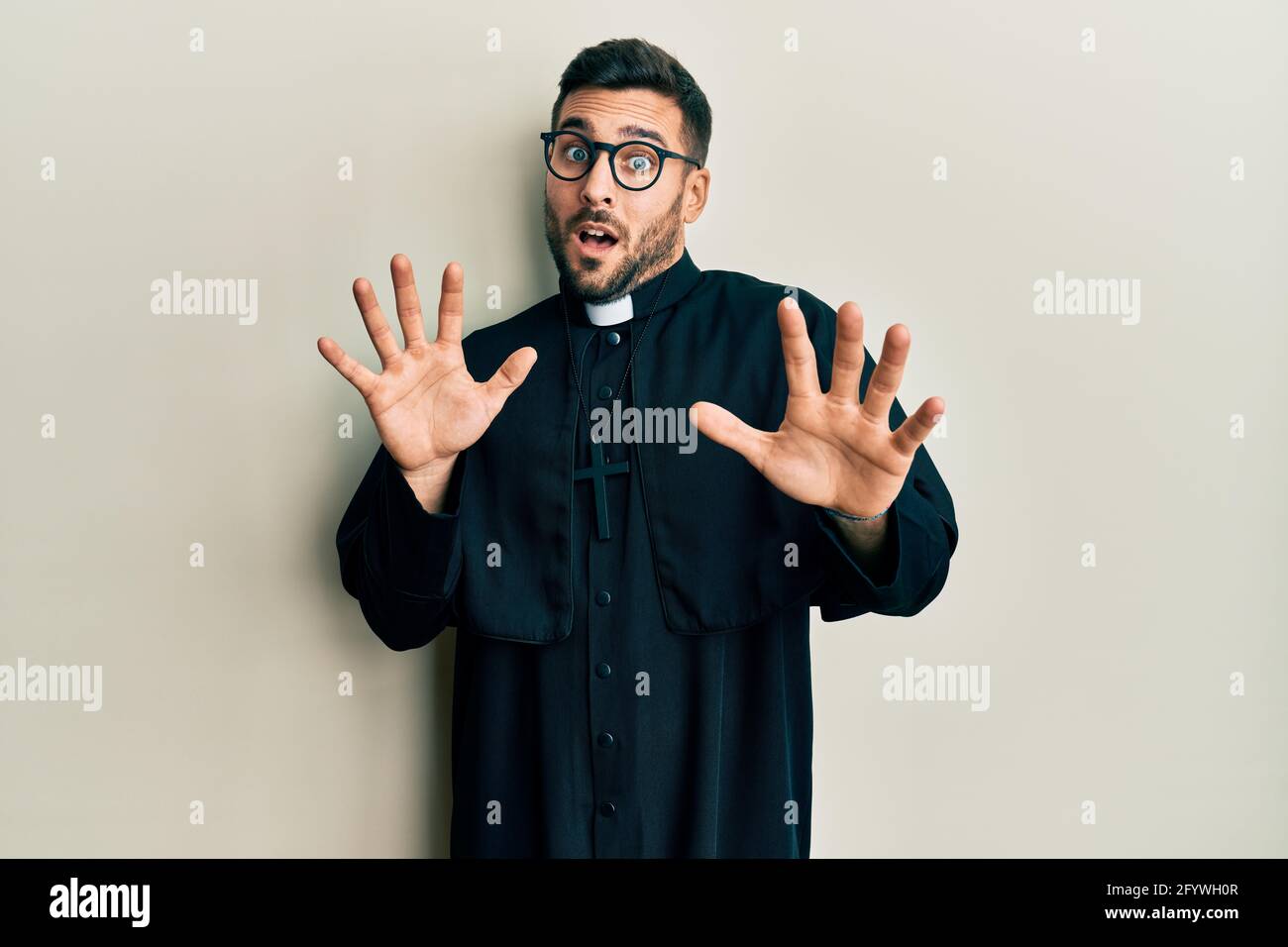 Young hispanic man wearing priest uniform standing over white ...