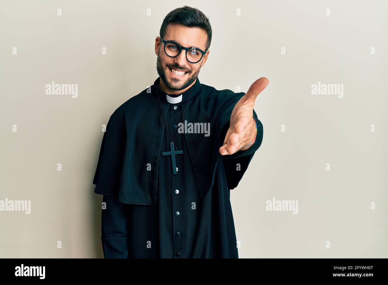 Young hispanic man wearing priest uniform standing over white ...