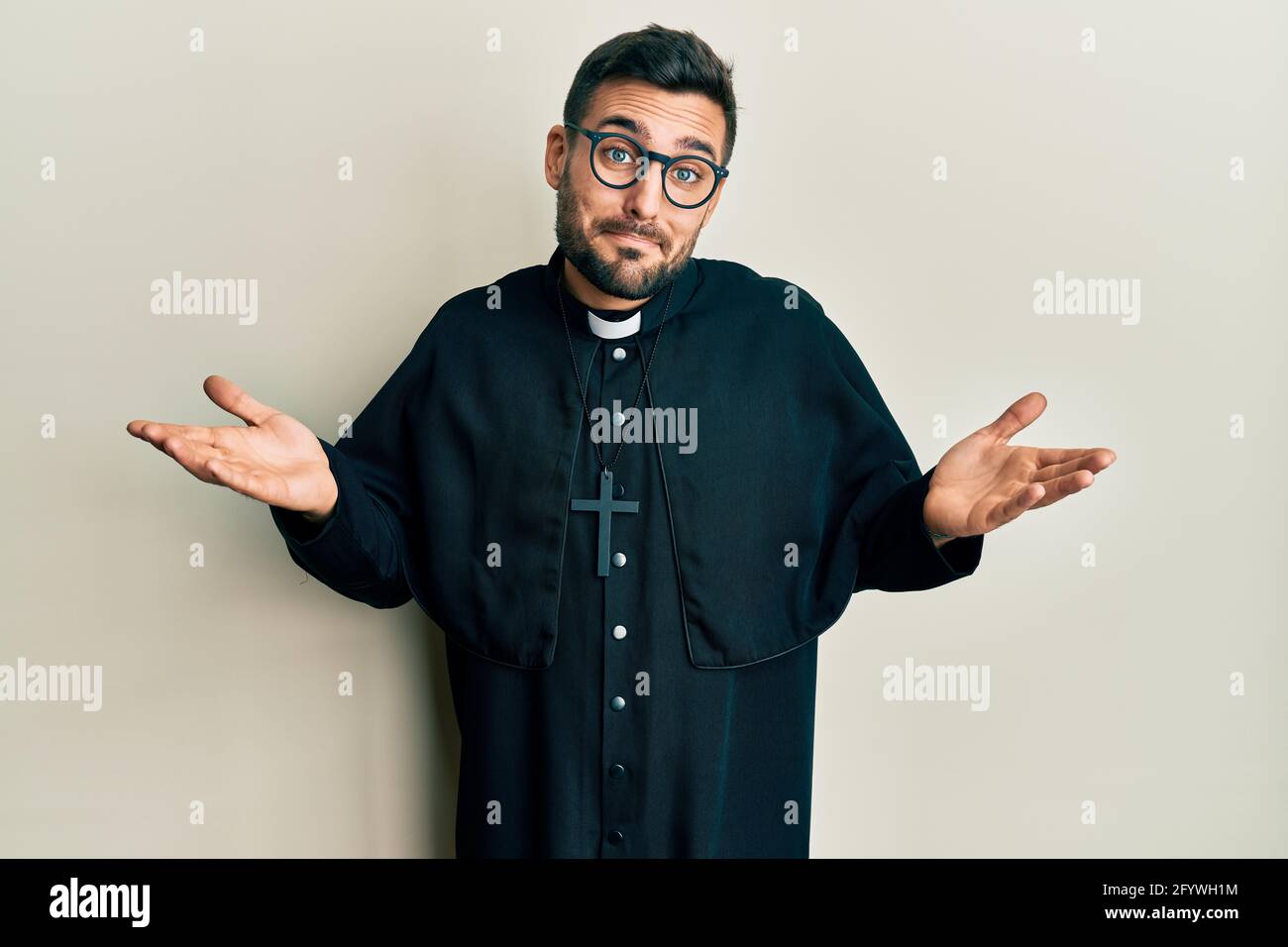 Young hispanic man wearing priest uniform standing over white ...