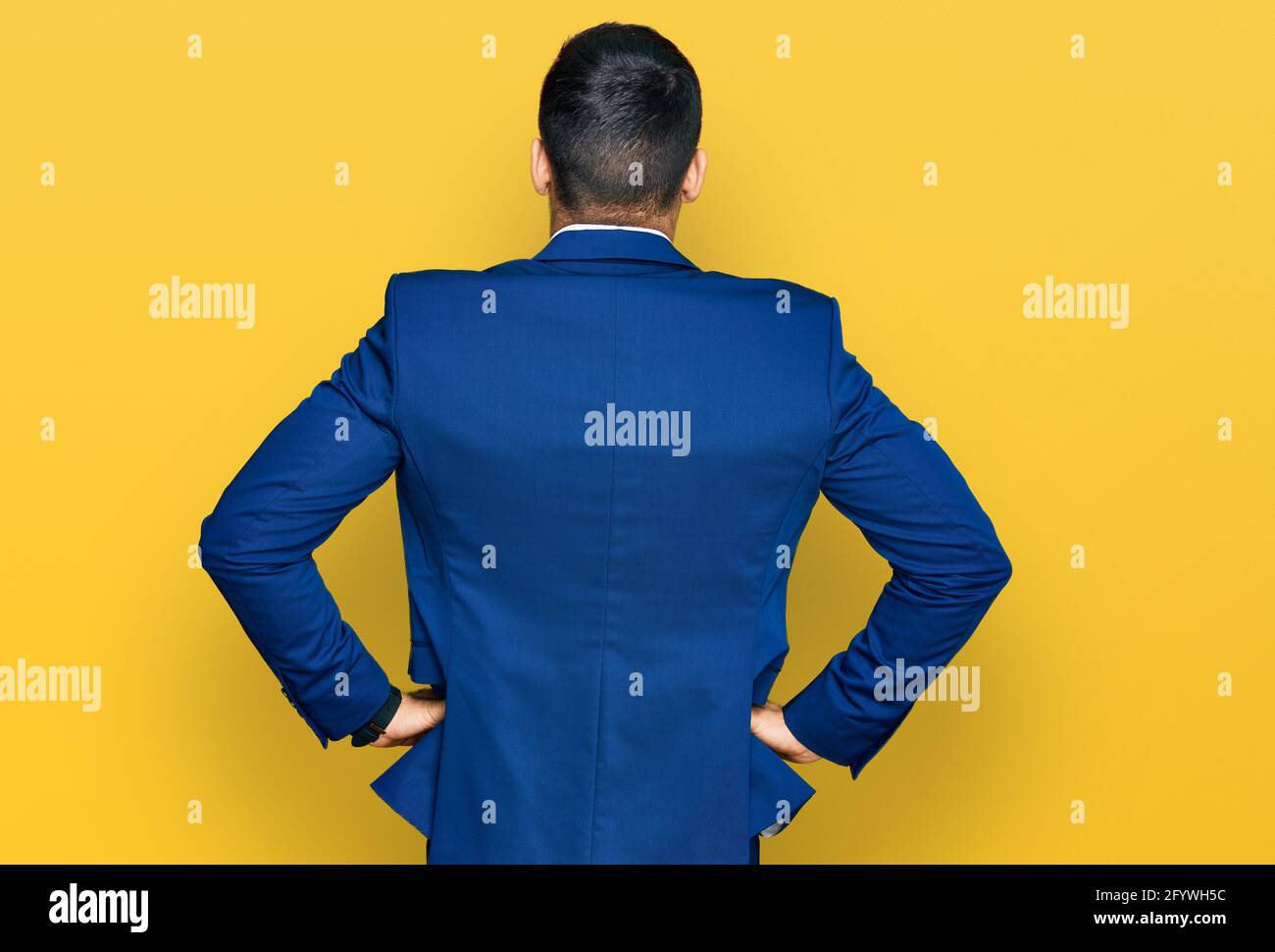 Young hispanic man wearing business jacket standing backwards looking ...