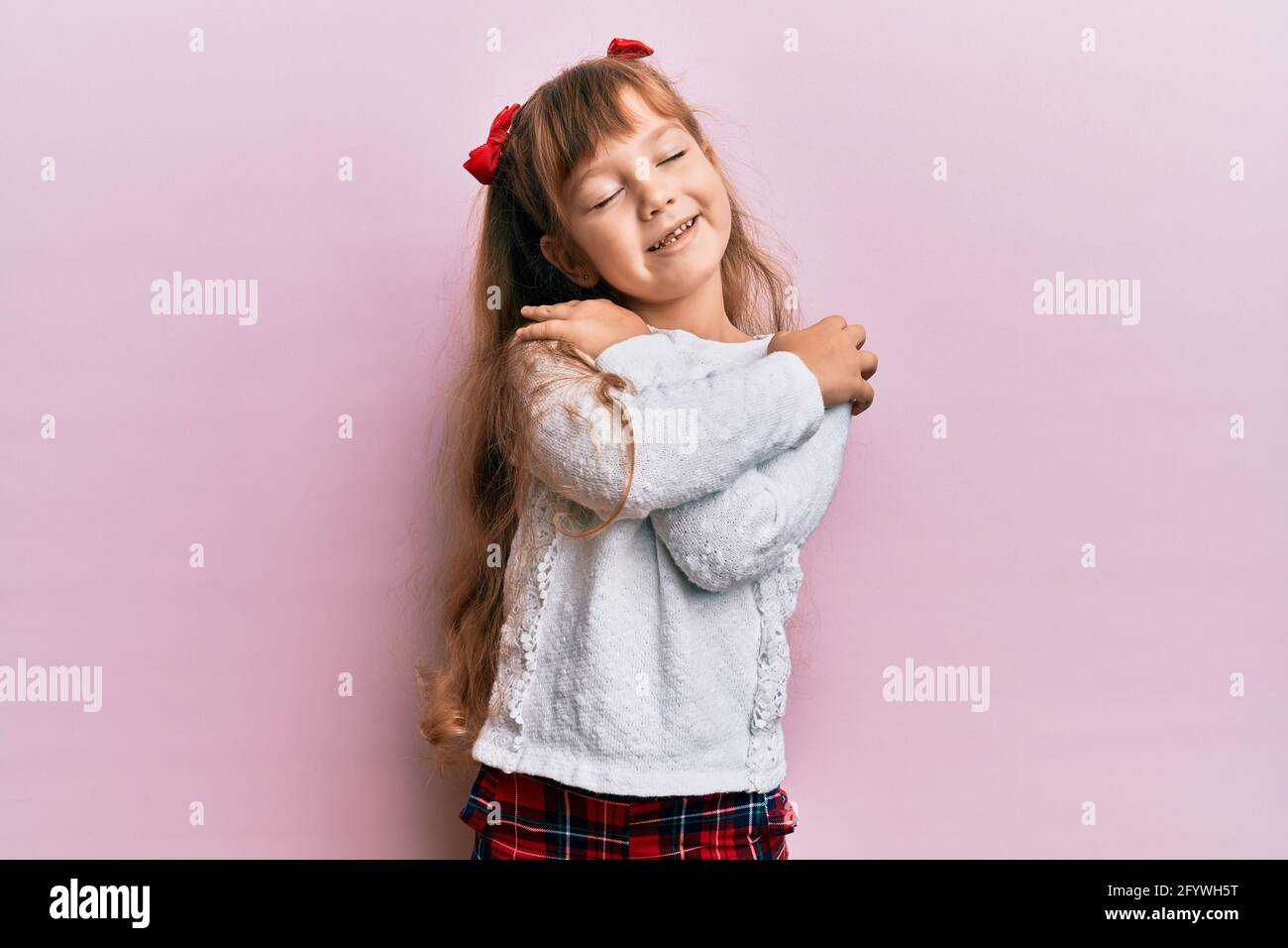 Little caucasian girl kid wearing casual clothes hugging oneself happy ...