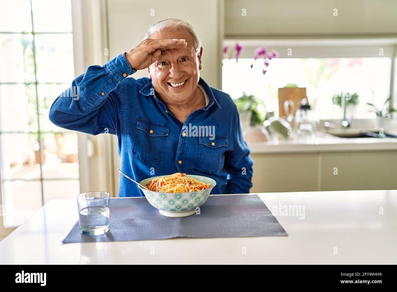 Senior man with grey hair eating pasta spaghetti at home very happy and ...