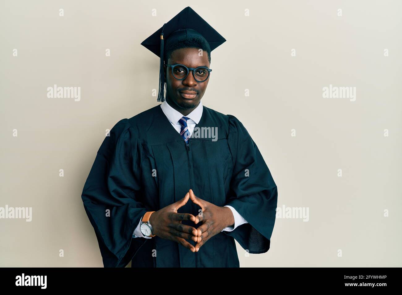 Handsome black man wearing graduation cap and ceremony robe hands ...