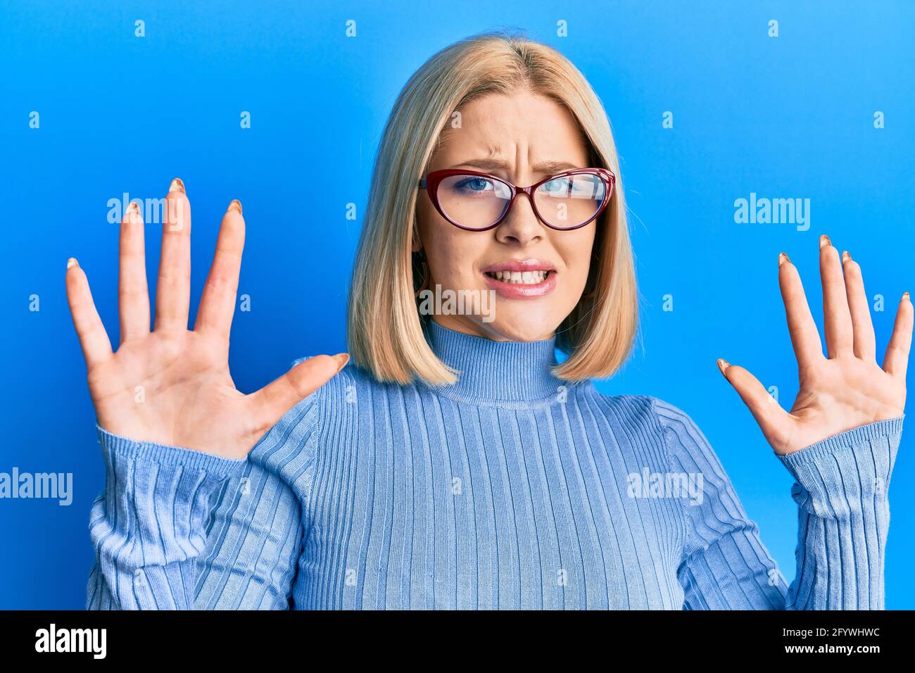 Young blonde woman wearing casual clothes and glasses afraid and ...