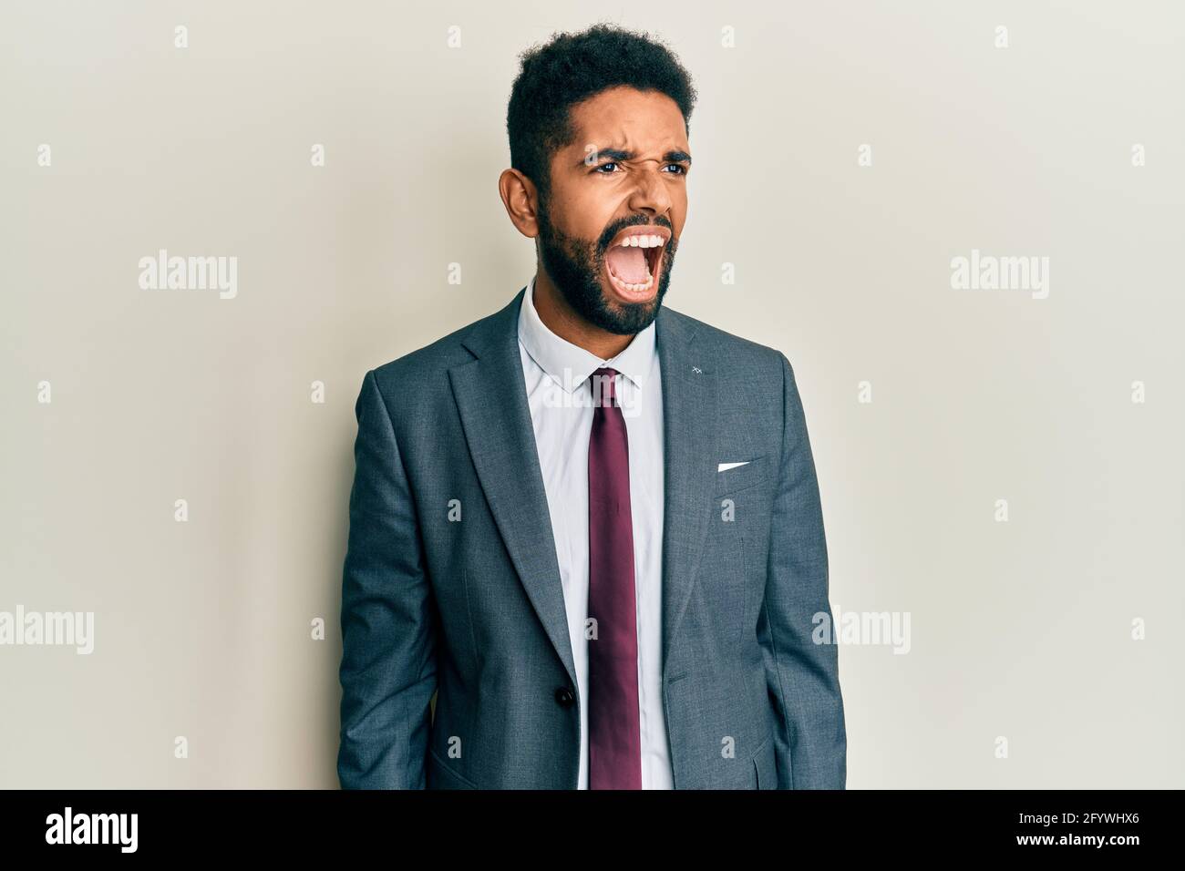 Handsome hispanic man with beard wearing business suit and tie angry ...