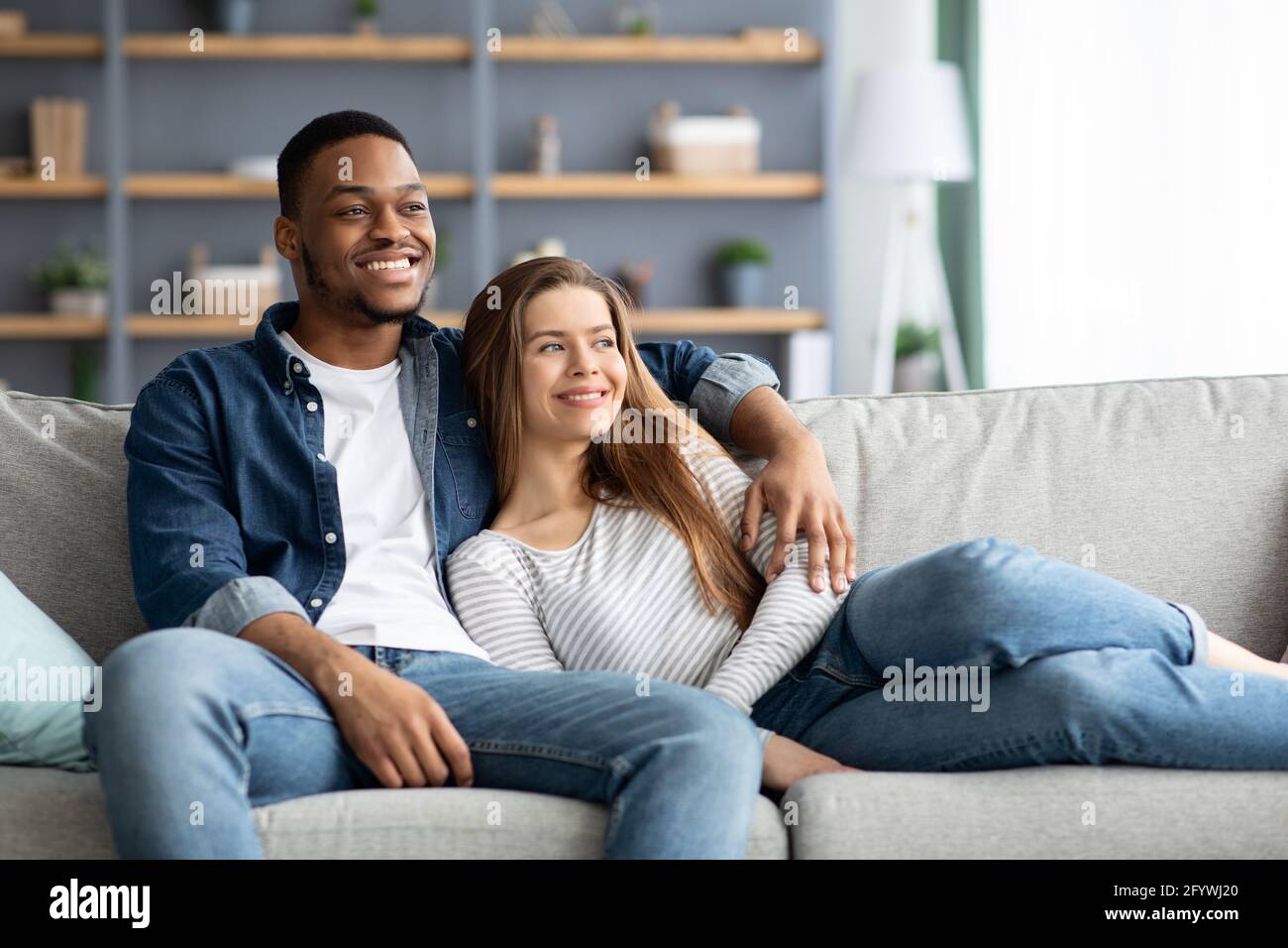 Loving young couple sitting on the couch at home hi-res stock ...