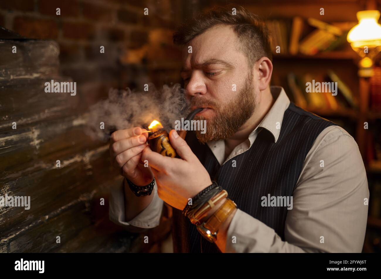 Bearded man lights smoking pipe with a match Stock Photo - Alamy
