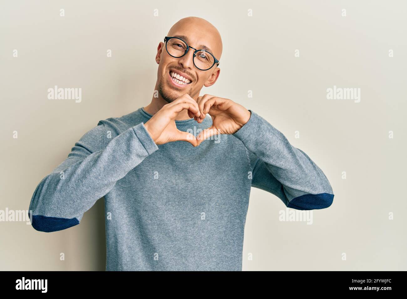 Bald man with beard wearing casual clothes and glasses smiling in love ...