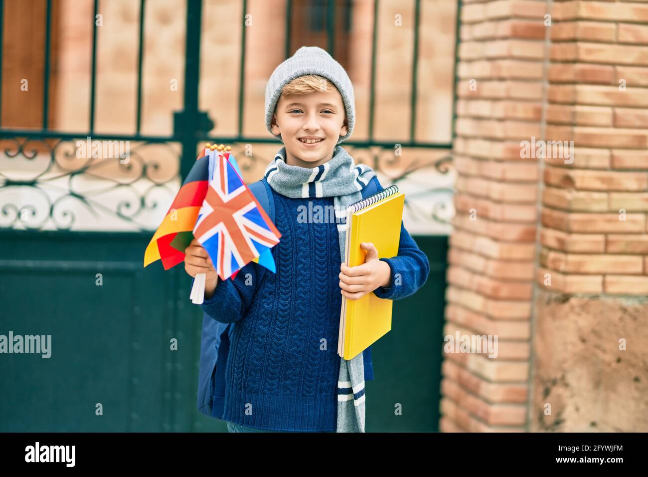 Adorable blond student kid smiling happy holding flags of different ...