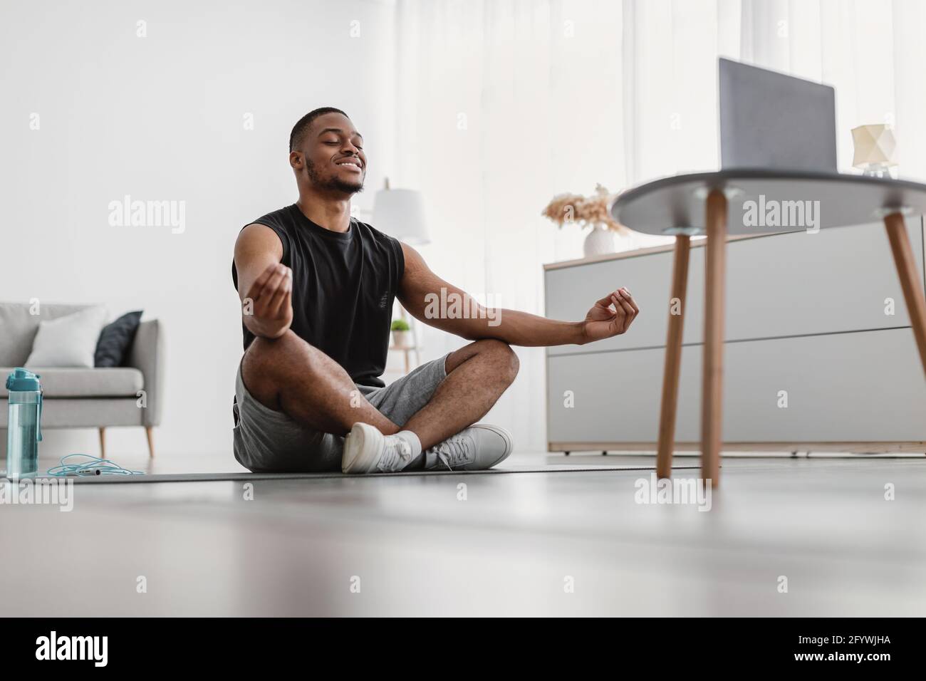 Black Male Meditating Sitting In Lotus Position Near Laptop Indoor ...
