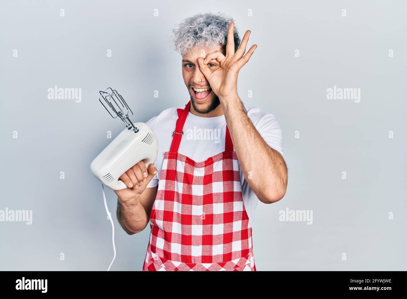 Young hispanic man with modern dyed hair holding food processor mixer ...