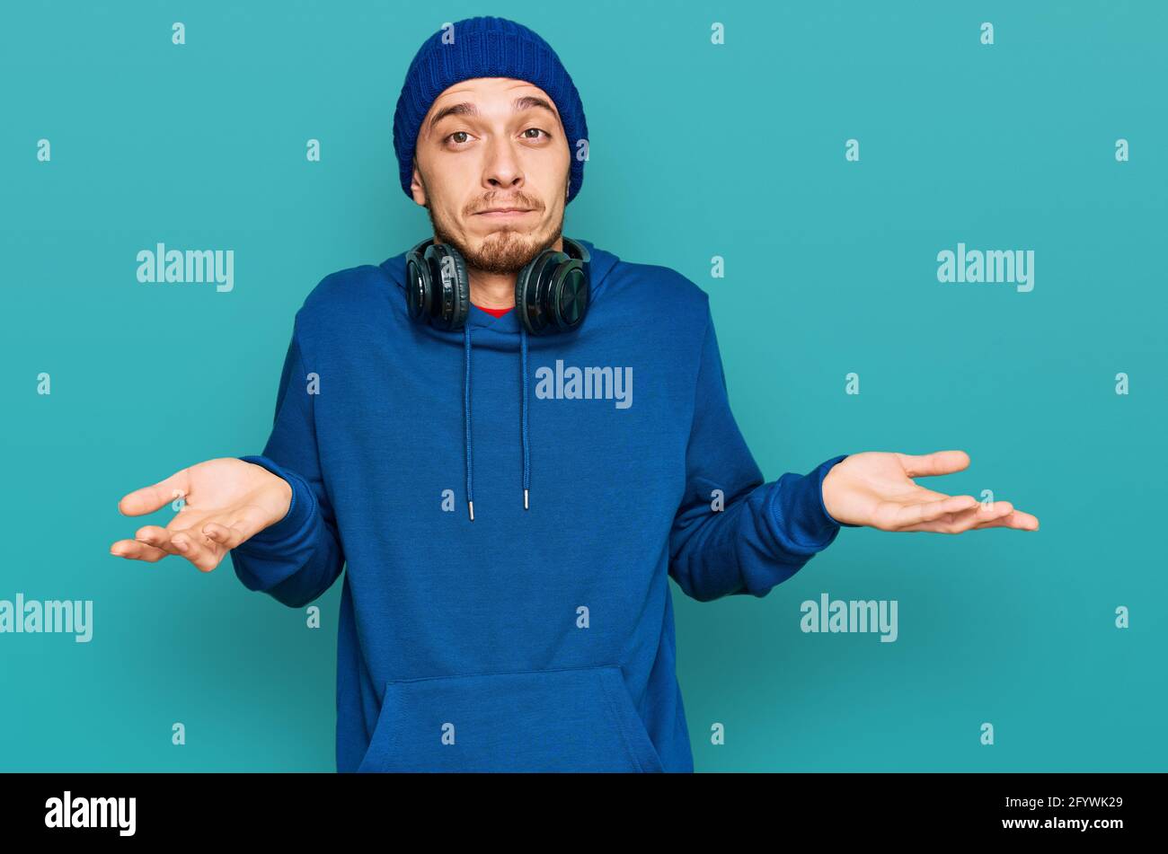 Hispanic young man wearing sweatshirt and wool hat clueless and ...