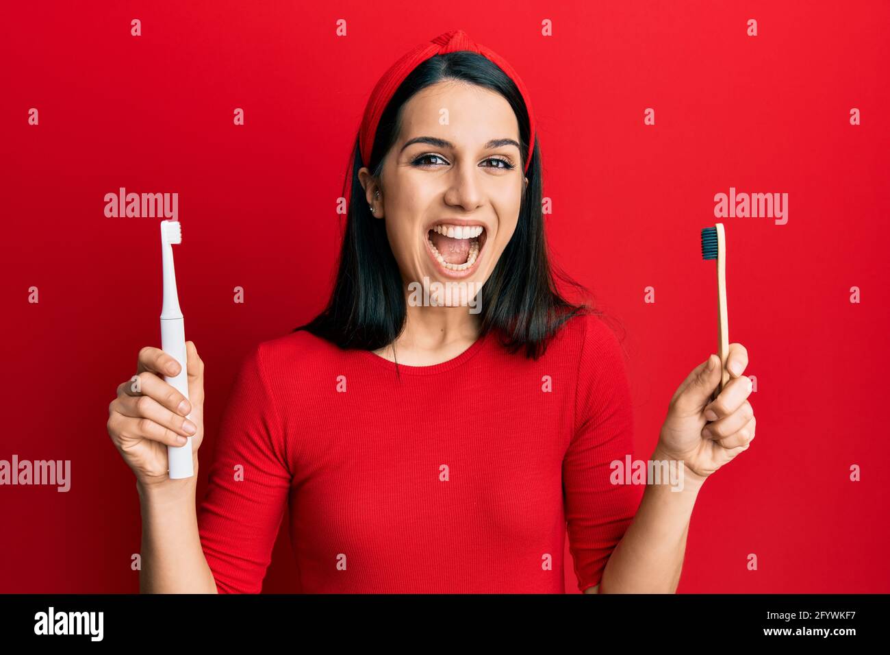 Young hispanic woman choosing electric toothbrush or normal teethbrush ...