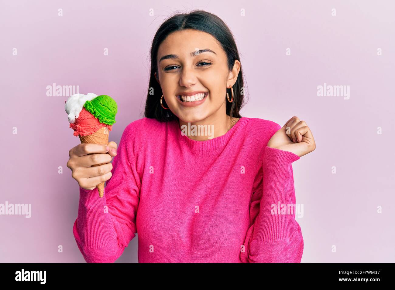 Young hispanic woman holding ice cream screaming proud, celebrating ...