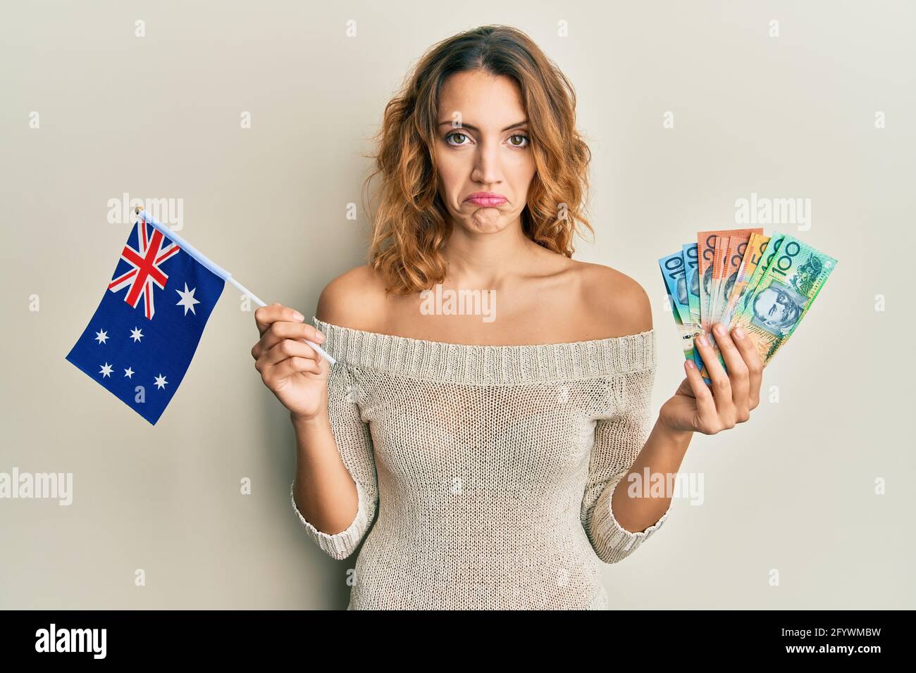 Young caucasian woman holding australian flag and dollars depressed and ...