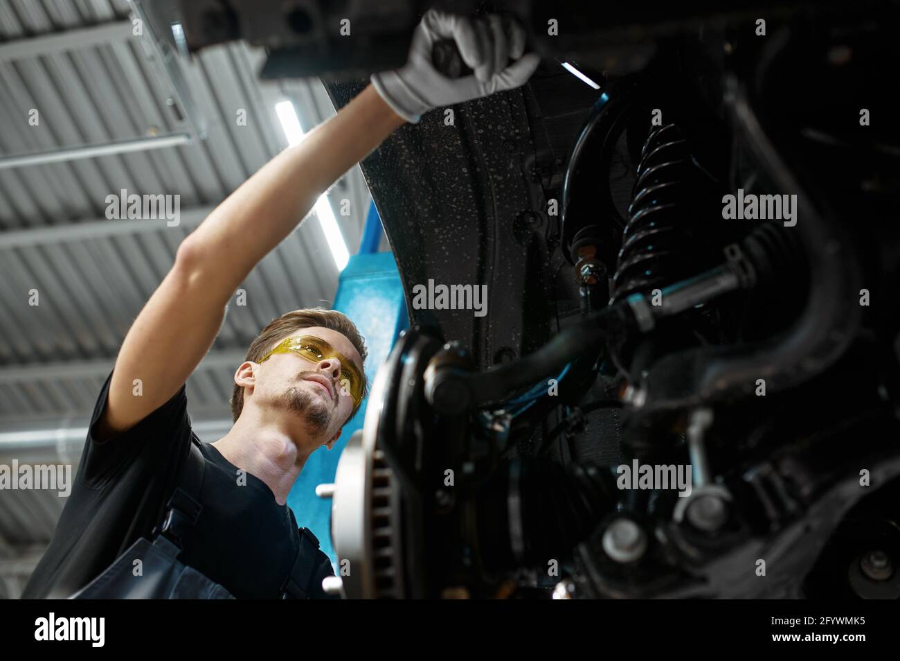 Male mechanic checks car suspension, auto service Stock Photo - Alamy