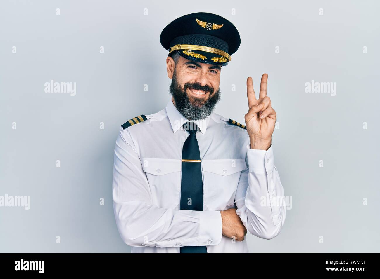 Young hispanic man wearing airplane pilot uniform smiling with happy ...