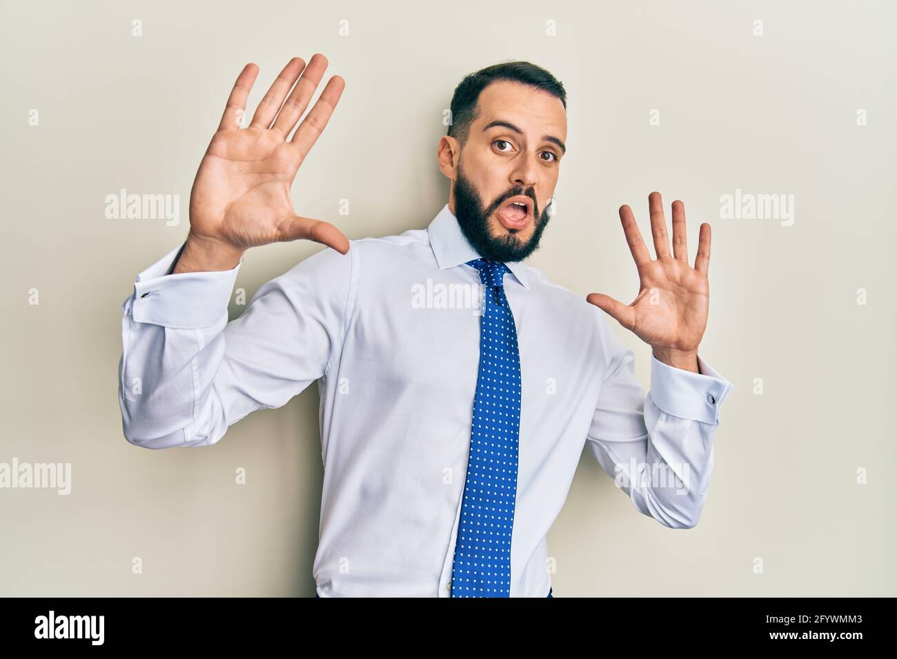 Young man with beard wearing business tie afraid and terrified with ...