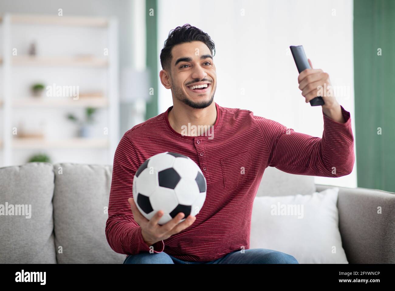 Emotional middle-eastern guy watching football game on TV Stock Photo ...