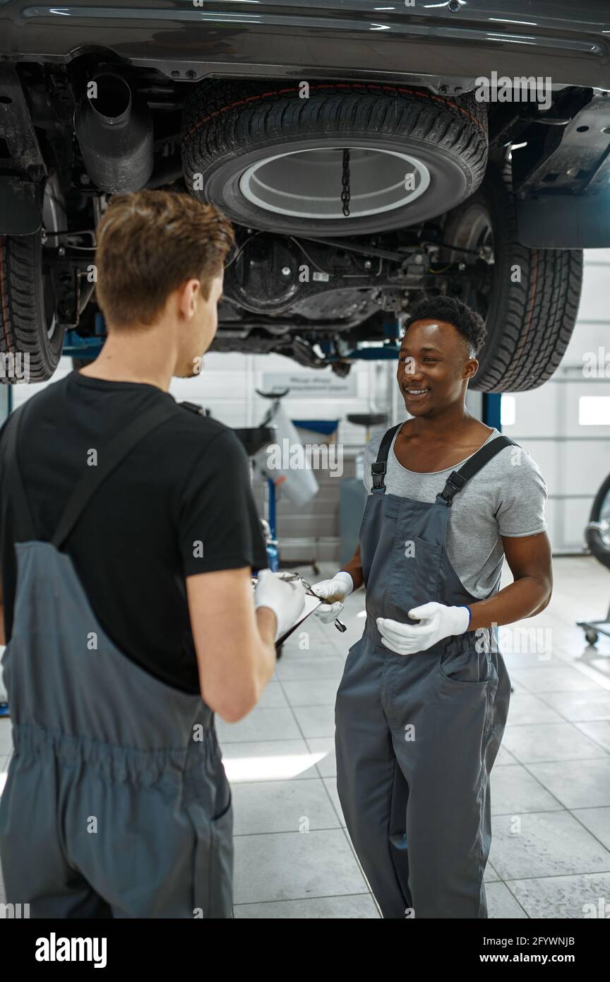 Male mechanics looking on checklist, car service Stock Photo - Alamy
