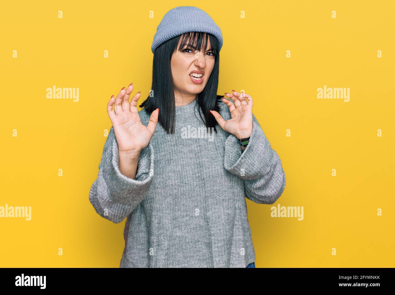 Young hispanic woman wearing cute wool cap afraid and terrified with ...