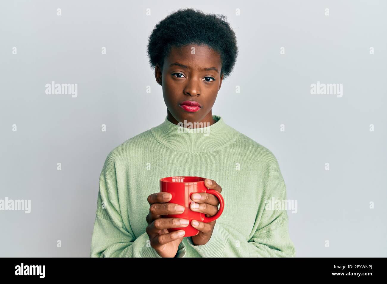 Young african american girl drinking a cup of coffee depressed and ...
