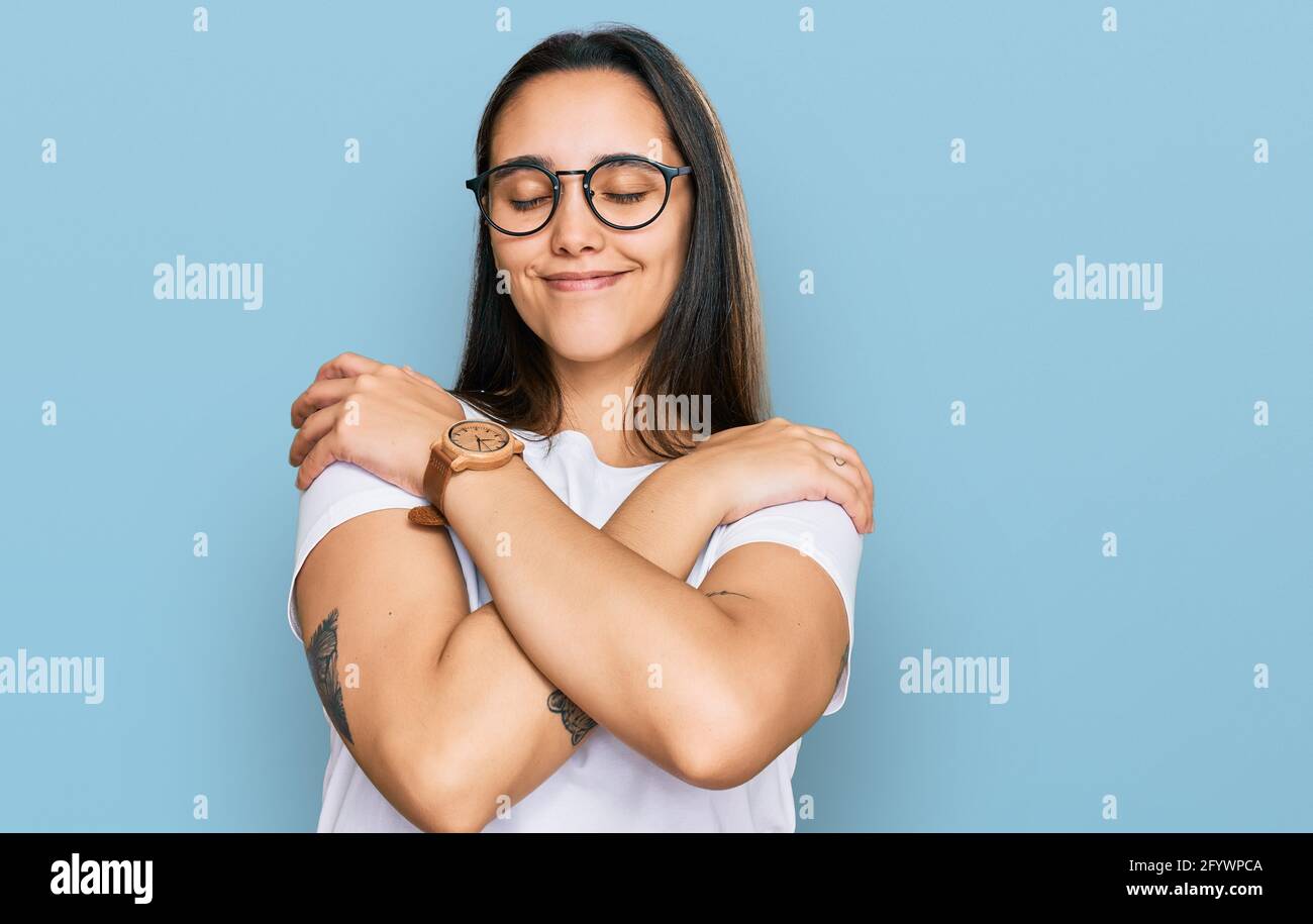 Young Hispanic Woman Wearing Casual White T Shirt Hugging Oneself Happy