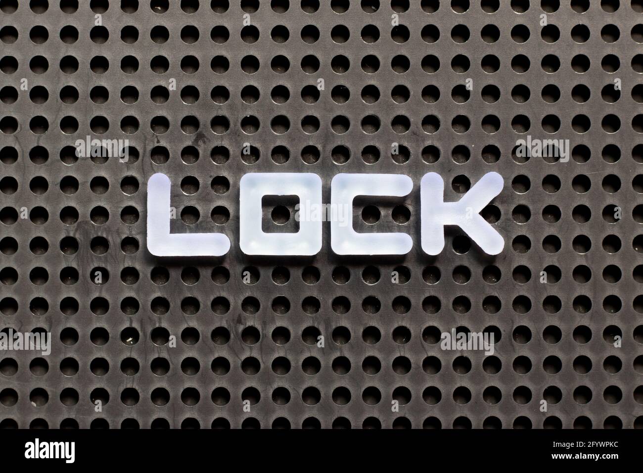 White color letter in word lock on black pegboard background Stock ...