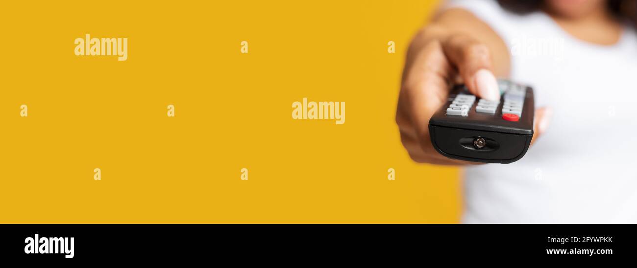 Black lady pointing remote controller to camera, switching channels ...