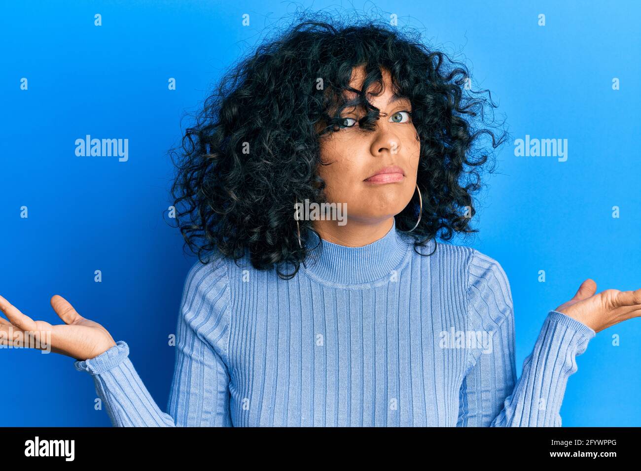 Young hispanic woman wearing casual clothes clueless and confused with ...