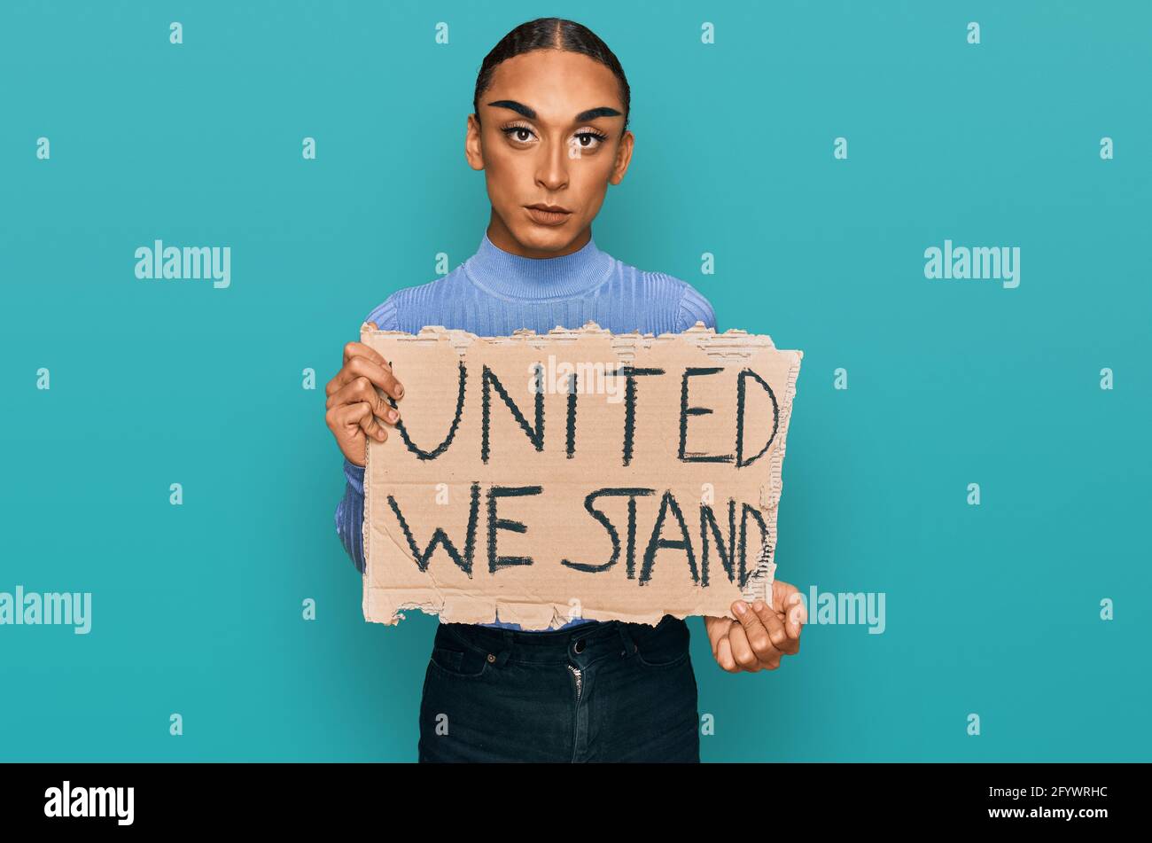 Hispanic transgender man wearing make up and long hair holding united ...