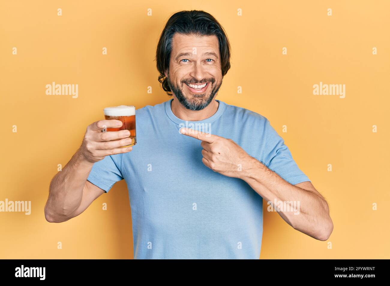 Middle age caucasian man drinking a pint of beer smiling happy pointing ...