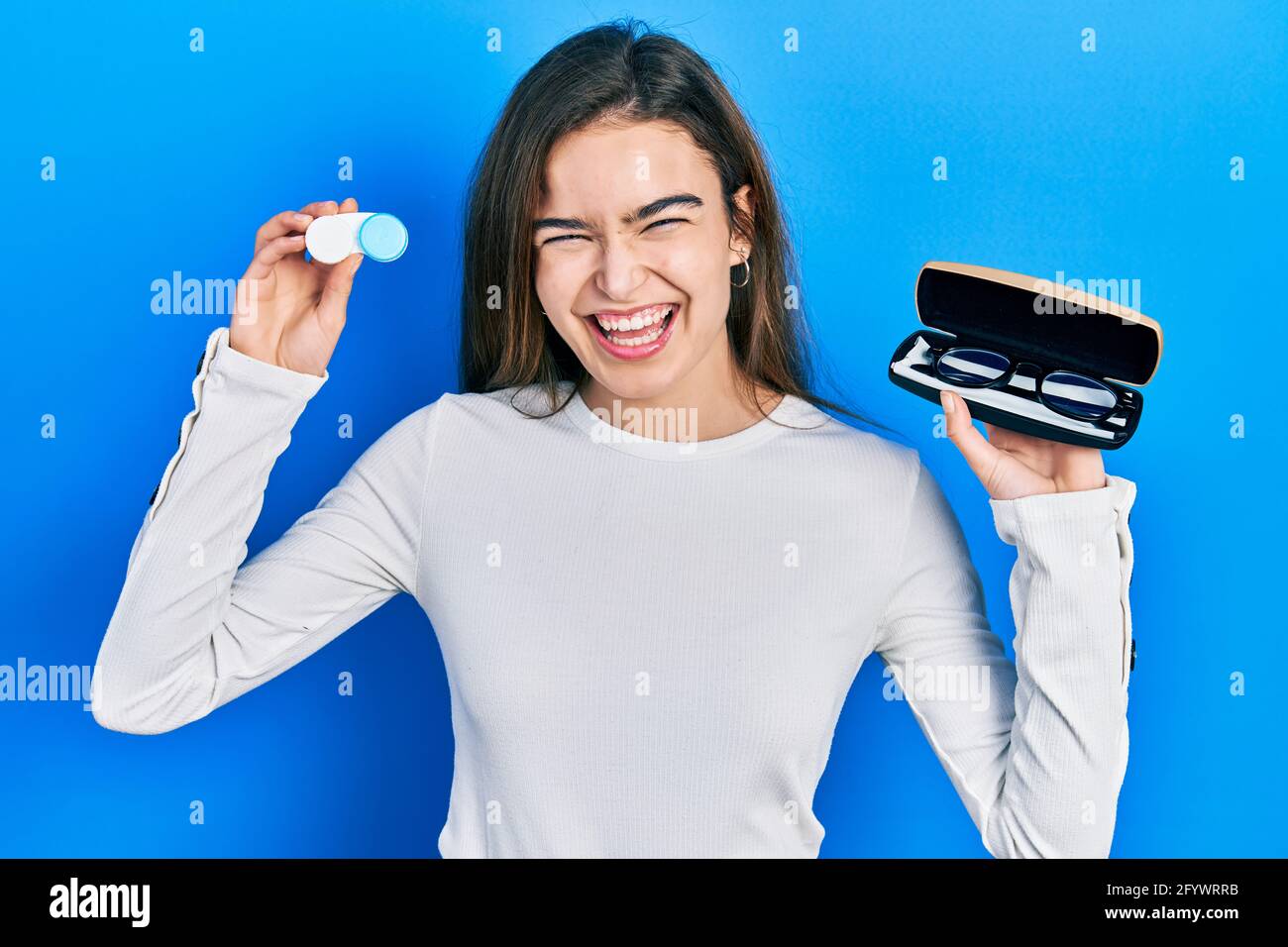 Young caucasian girl holding glasses and contact lenses smiling and ...