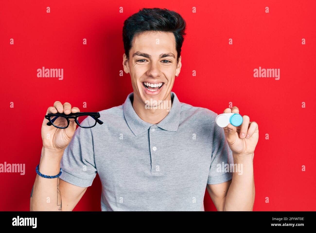 Young hispanic man holding glasses and contact lenses smiling and ...