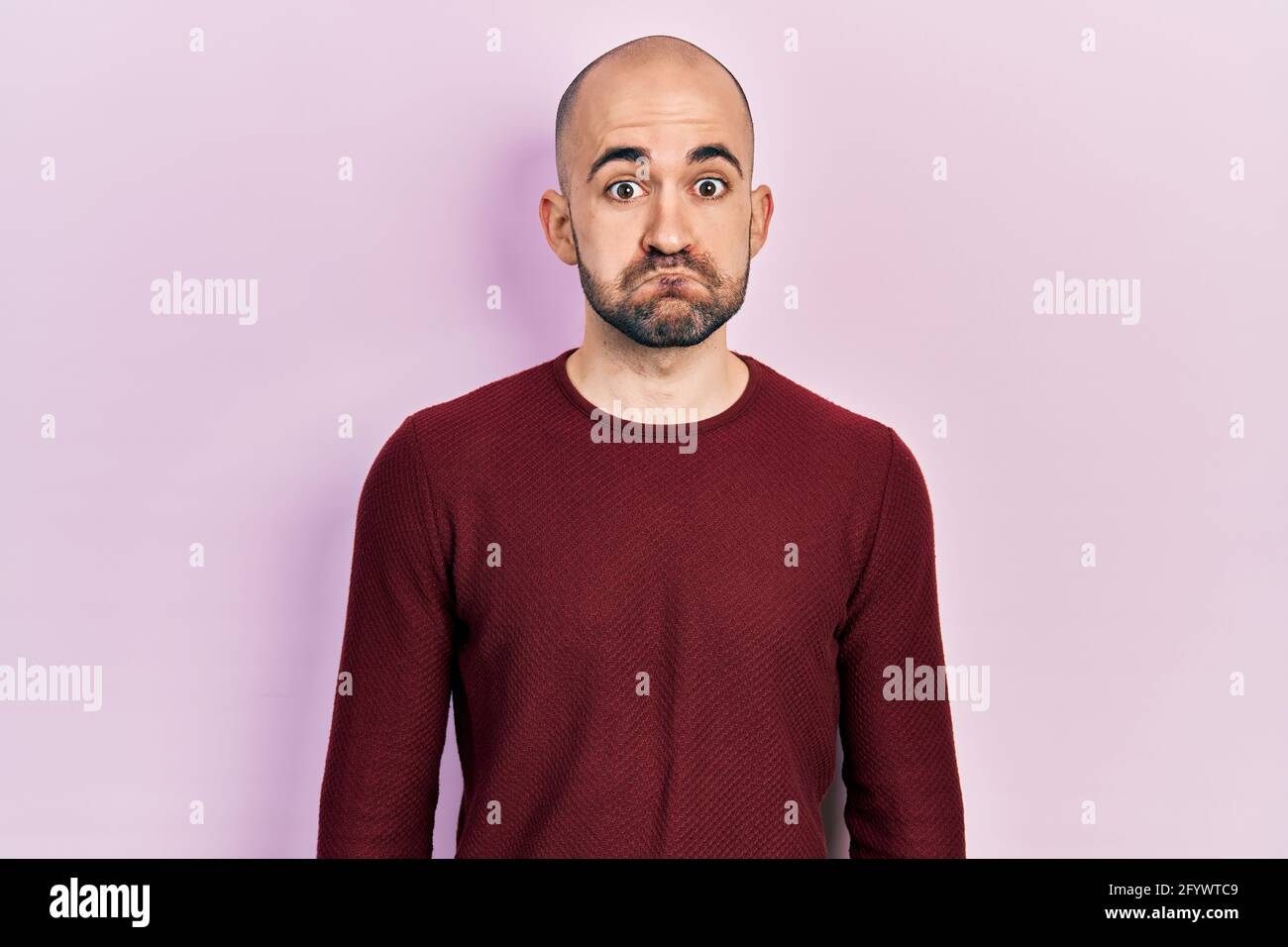 Young bald man wearing casual clothes puffing cheeks with funny face ...