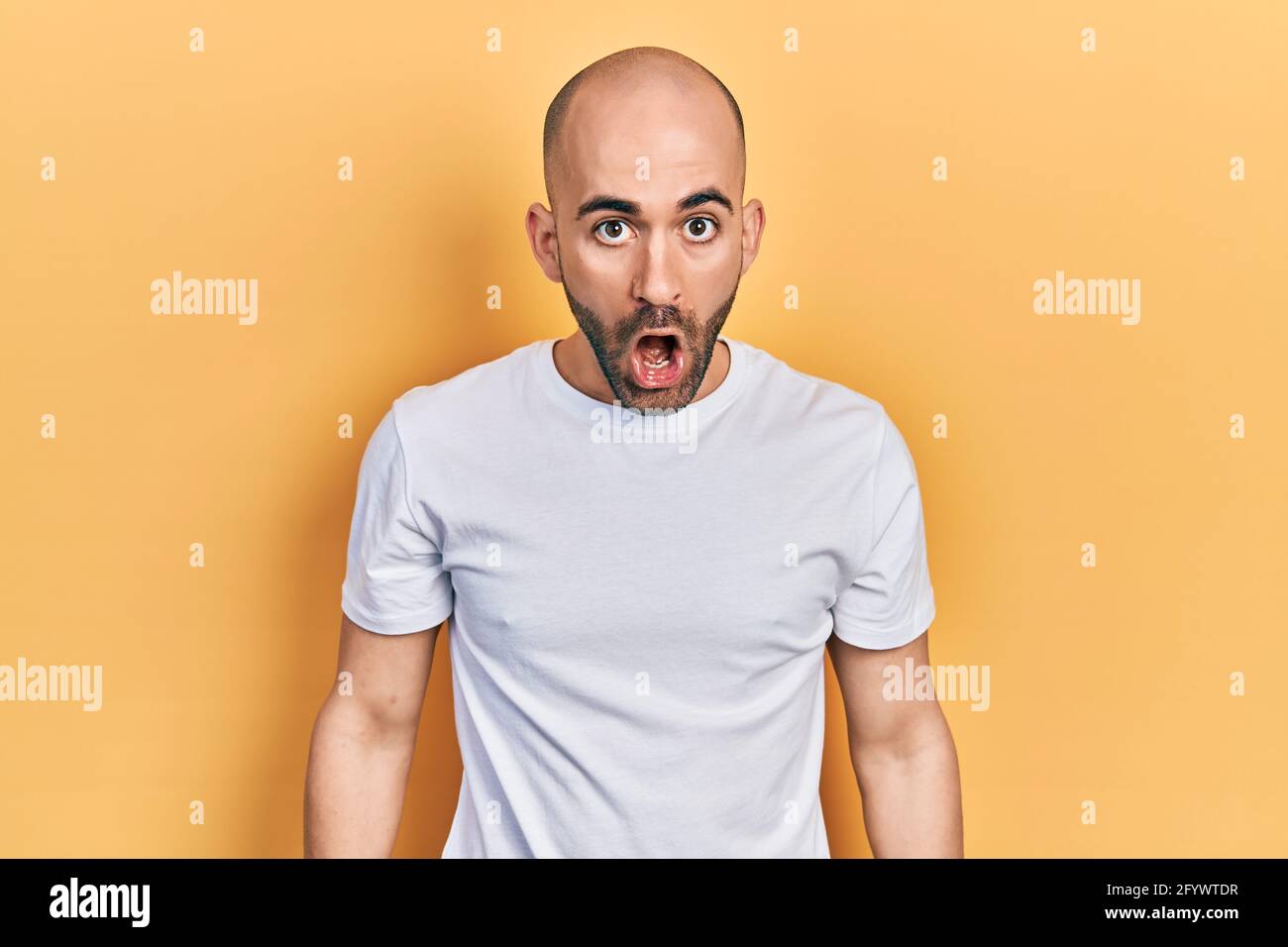 Young bald man wearing casual white t shirt afraid and shocked with ...