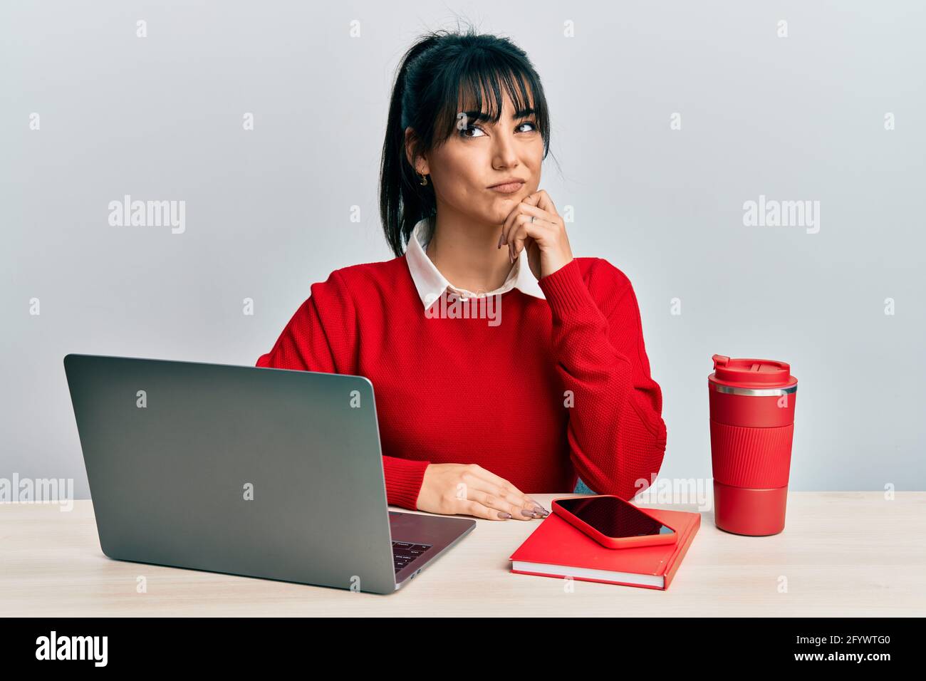 Young brunette woman with bangs working at the office with laptop ...