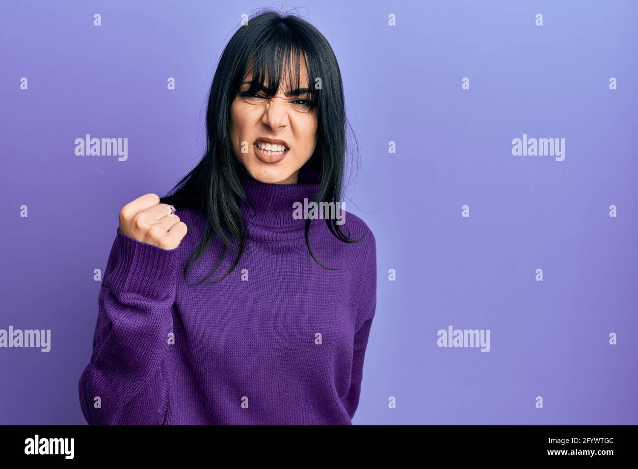 Young brunette woman with bangs wearing turtleneck sweater angry and ...