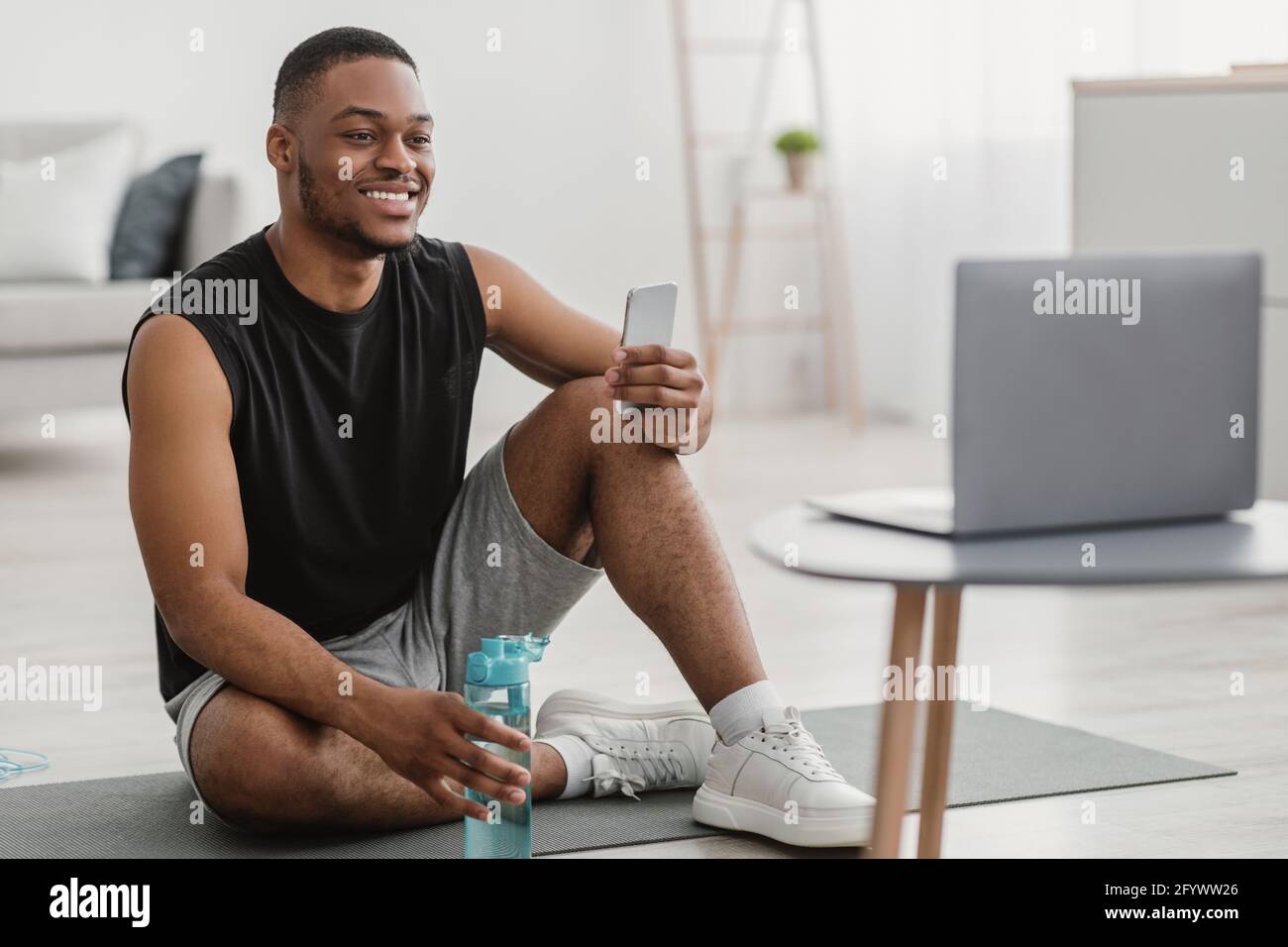 African Guy Holding Smartphone Watching Online Training On Laptop ...