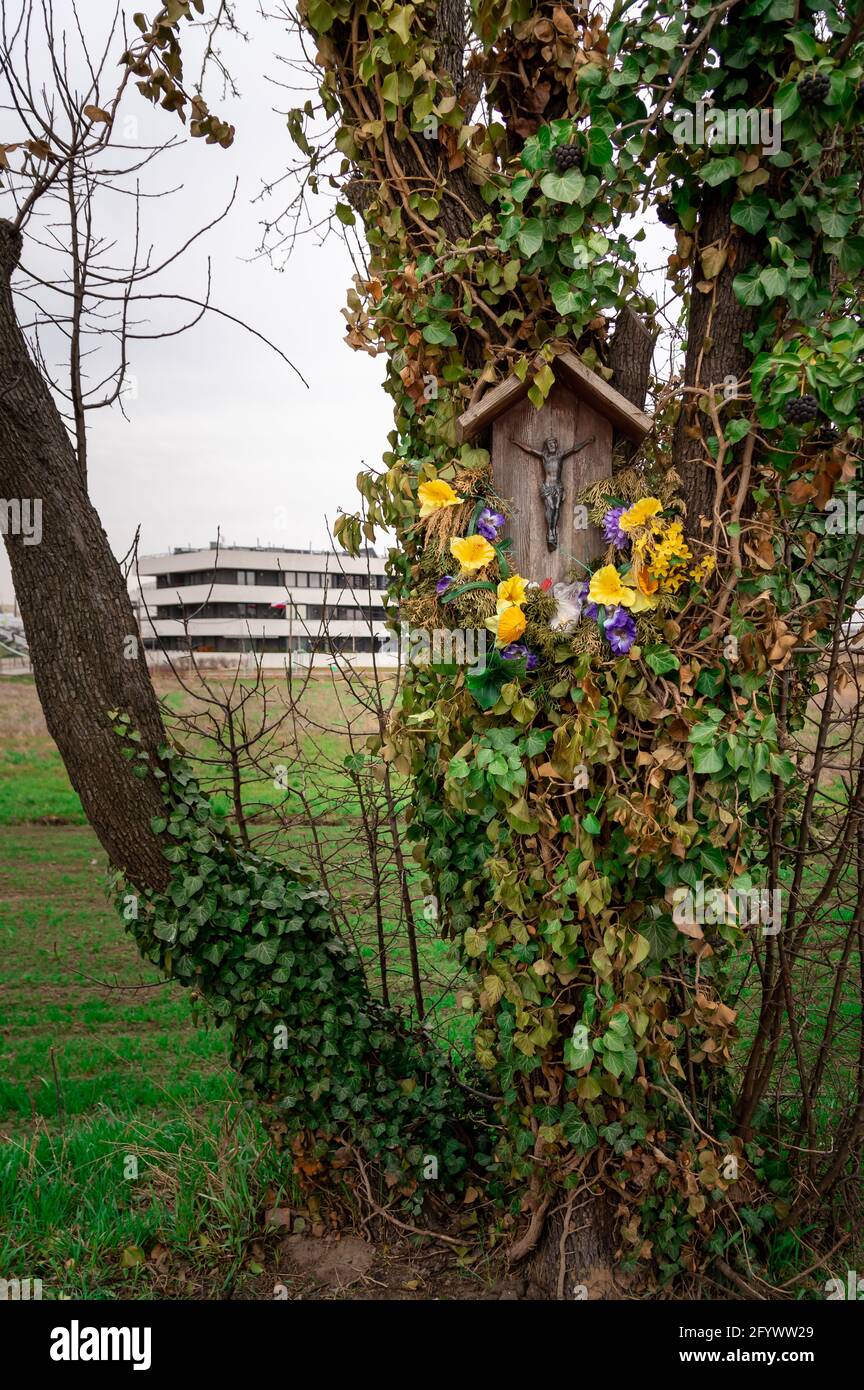A vertical shot of a small statue of Jesus Christ on a tree decorated ...