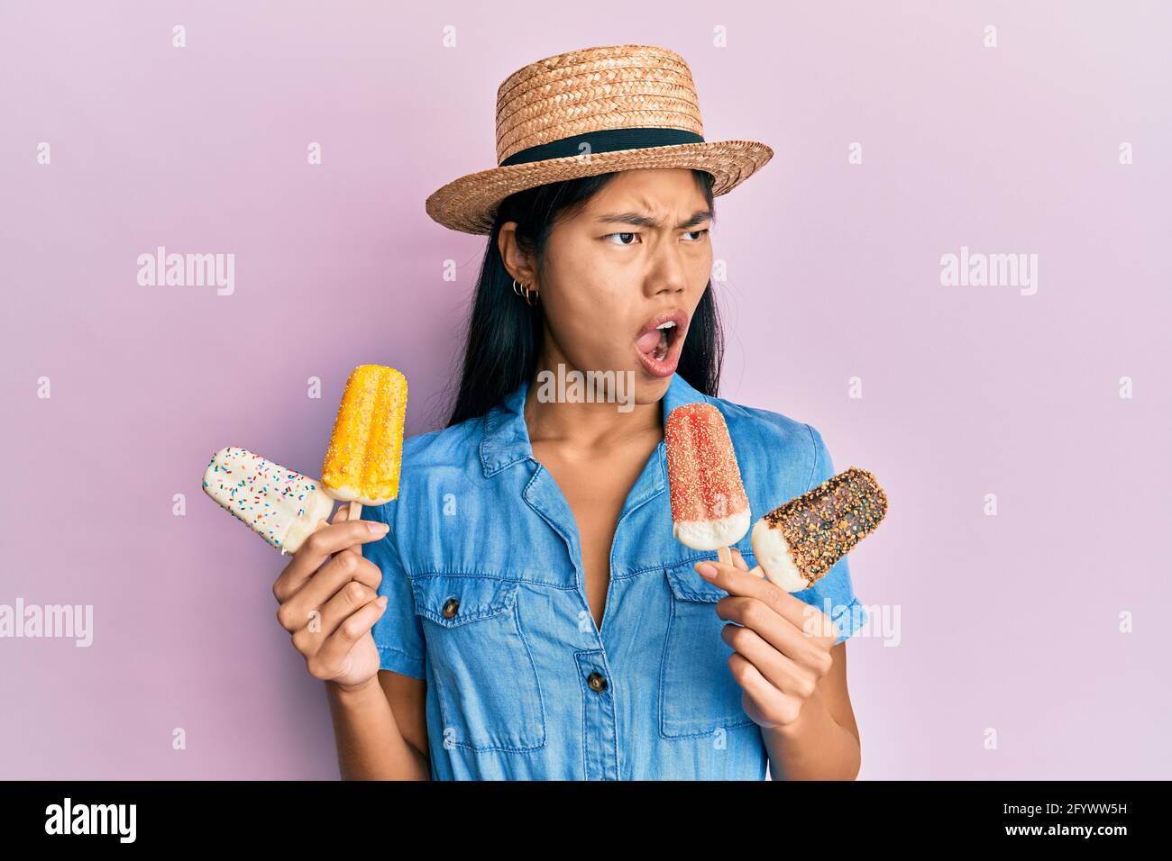 Young chinese woman wearing summer style holding ice cream angry and ...