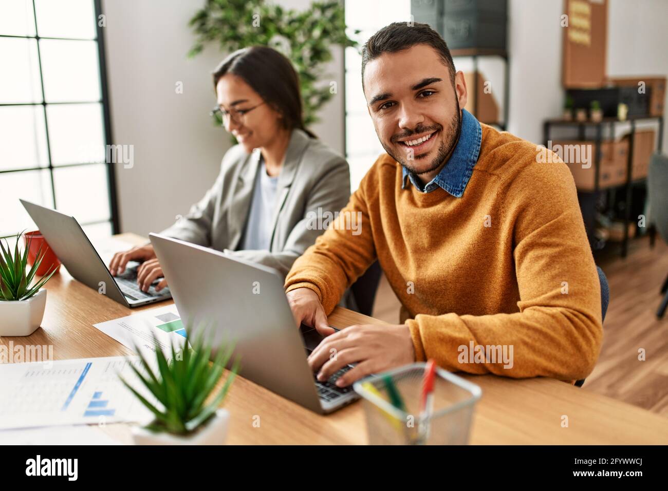 Two business workers smiling happy working sitting on desk at the ...