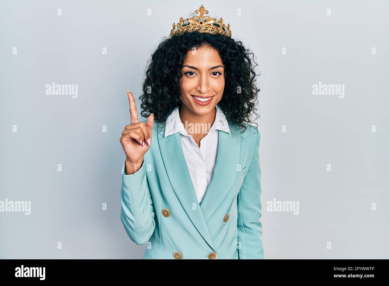 Young latin girl wearing business clothes and queen crown pointing ...