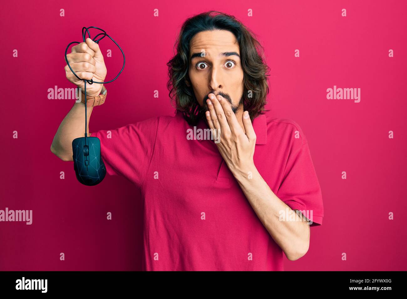 Young hispanic man holding mouse computer covering mouth with hand ...
