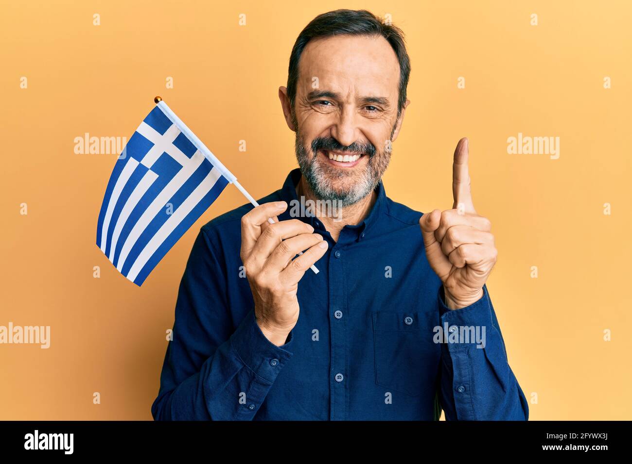 Middle age hispanic man holding greece flag smiling with an idea or ...